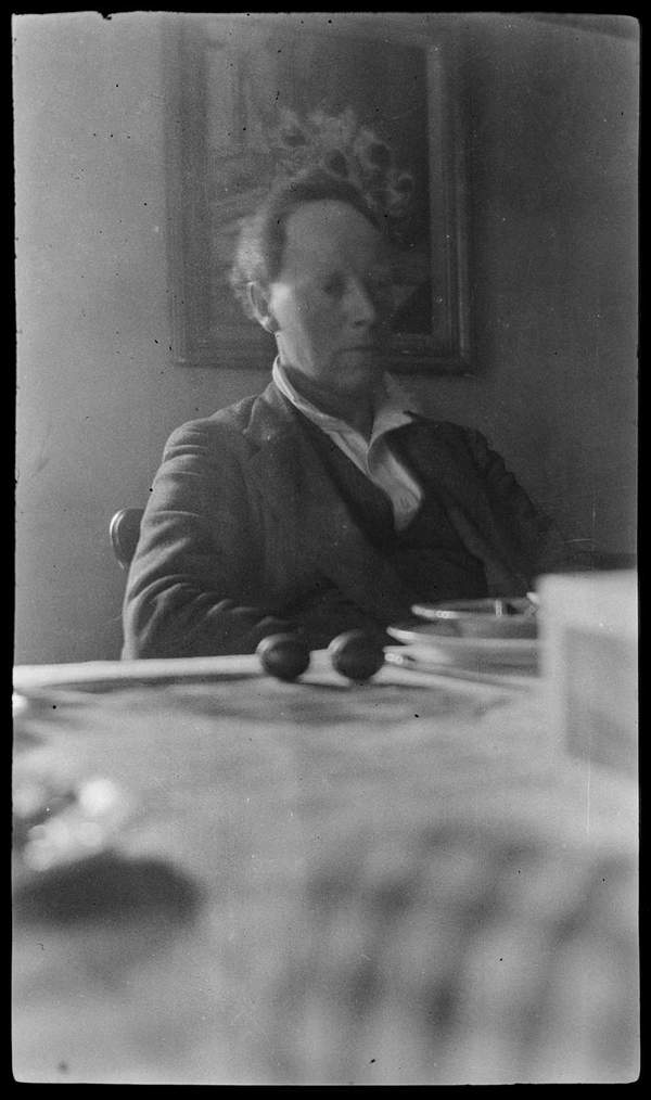 Black and white negative of Clive Bell seated at a table, in front of a ...