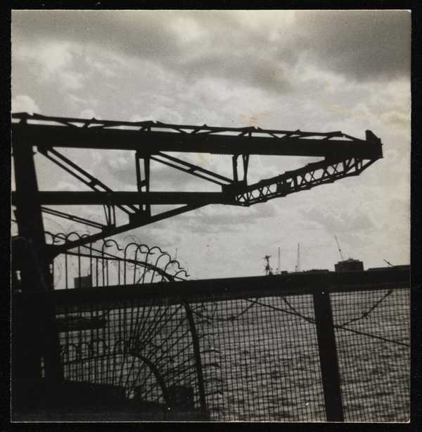 Black and white photograph of the arm of a crane extended over water ...