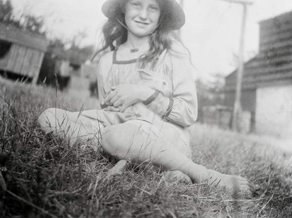 Black and white negative of Pamela Fry holding a rabbit while seated on ...