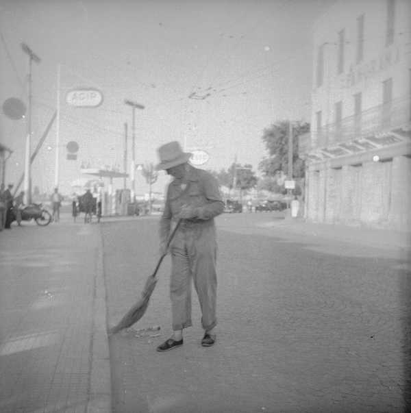 Photograph of an unidentified man sweeping rubbish in the street ...