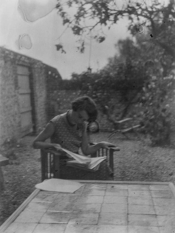 Black and white negative of Frances Marshall seated outdoors, reading a ...