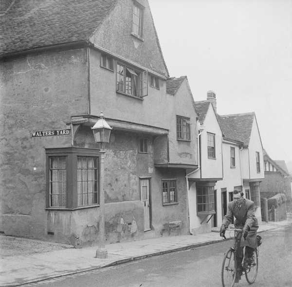 Photograph showing an unidentified man on a bicycle beside Walters Yard ...