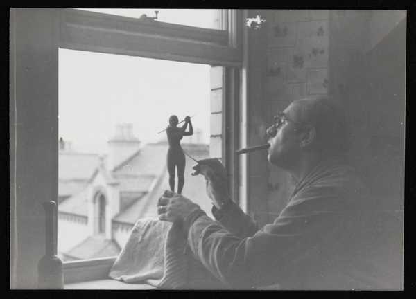 Photograph of Paul Hamann working on a small carved figure‘, Major H. O ...