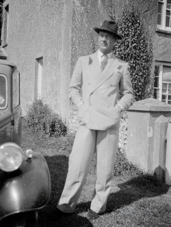 Black and white negative of Angus Davidson posing in front of the house ...